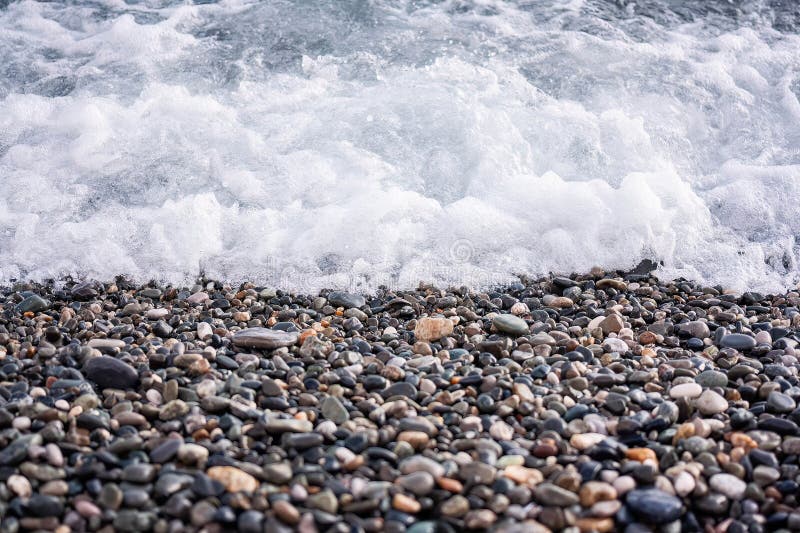 Pebbles on the Shore in Focus and in the Background the Surf and Waves ...