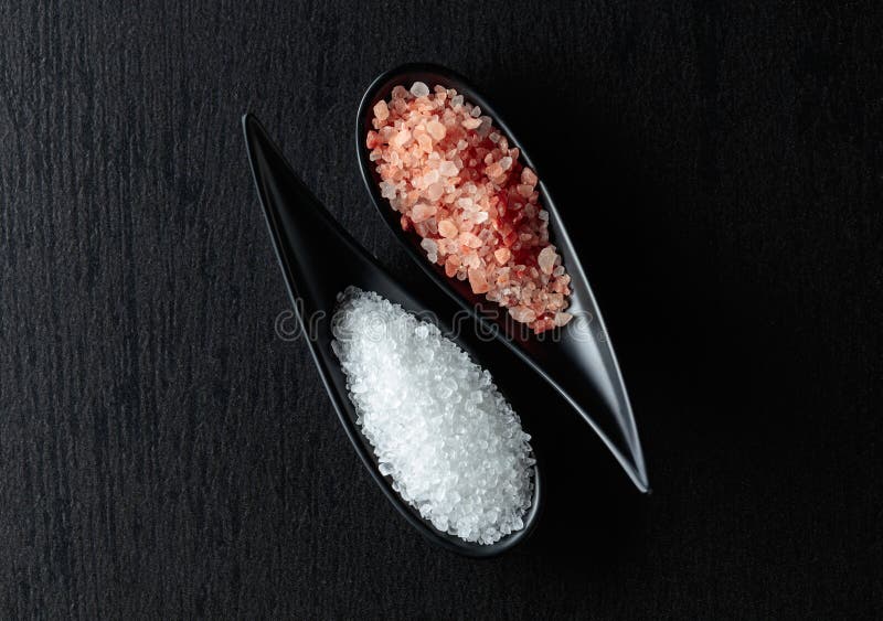 White Sea Salt and Pink Himalayan Salt on a Black Ceramic Table Stock ...