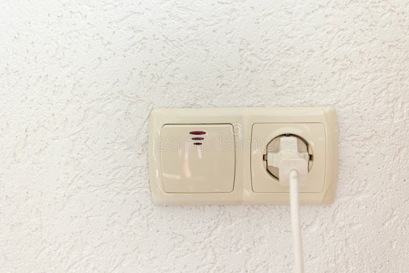 White Socket with Plug and Light Switch on an Empty Wall with Space for ...