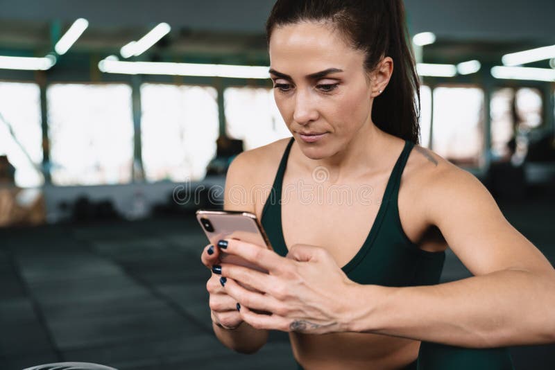 White Sportswoman Using Cellphone while Working Out in Gym Stock Photo ...