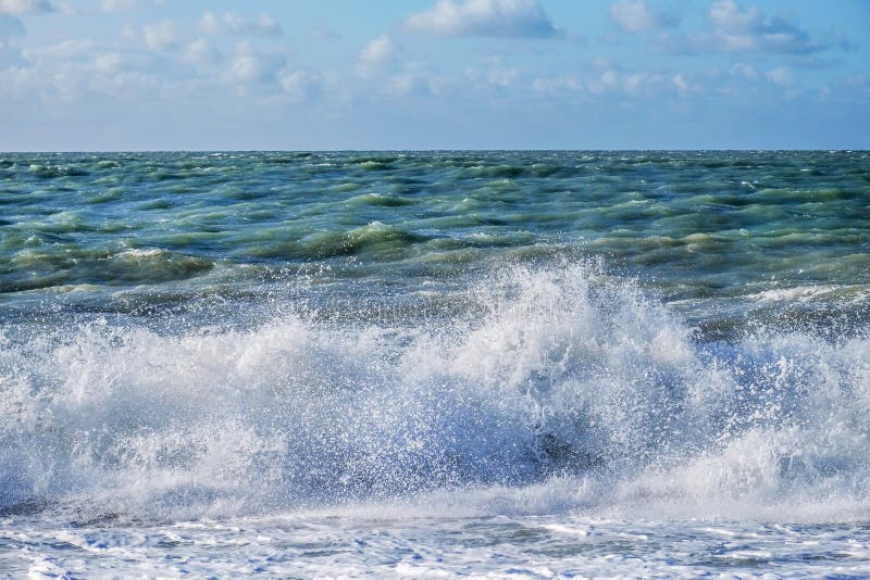 White Spray of a Wave Breaking on the Beach with a Rough Sea and Sky ...