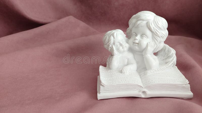 A White Statuette of Two Angels Reading a Book Stock Photo - Image of ...