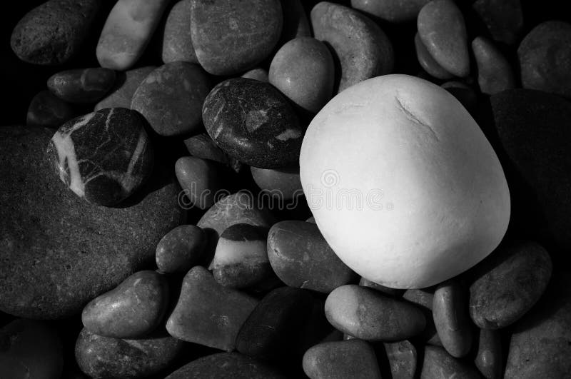 White Round Stone among Different Black Stones Stock Image - Image of ...