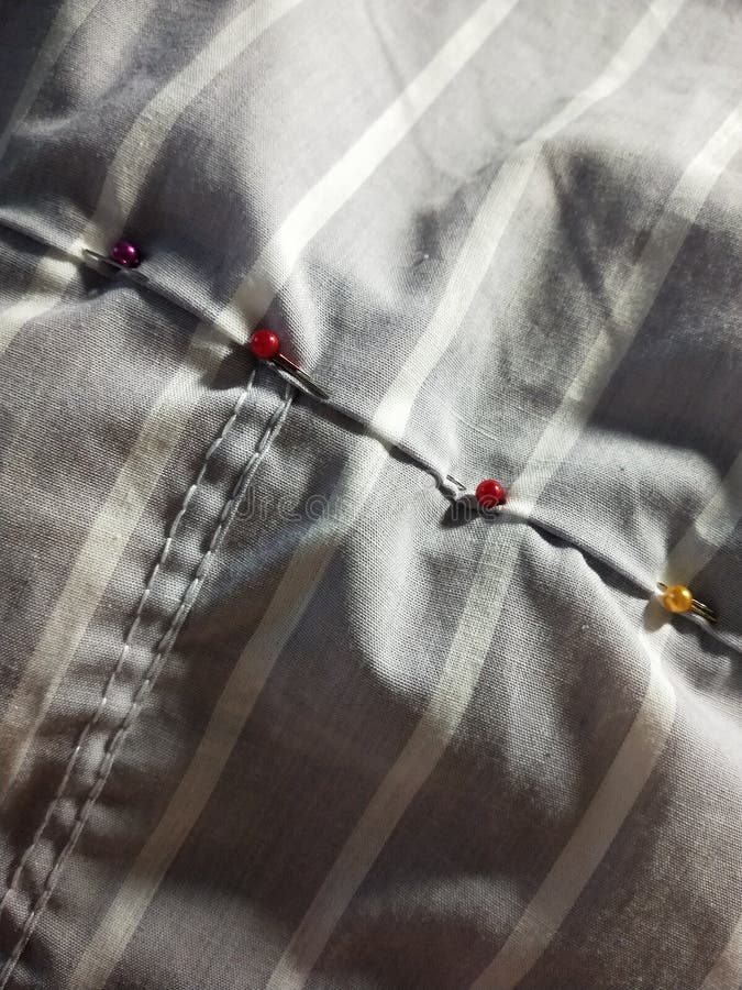 White Striped Fabric Stitched with White Thread and Multi Colored Pins ...