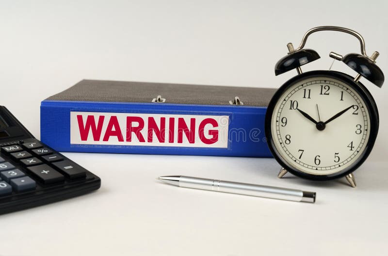 On a White Surface, an Alarm Clock Calculator and a Folder with the ...