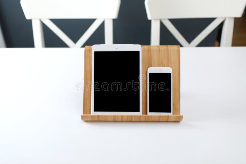 A White Tablet and a Smartphone with a Black Screen on a Stand on a ...