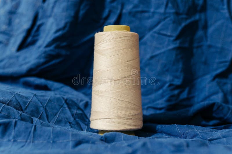 An Image of a White Thread Spool on a Blue Cloth Stock Image - Image of ...