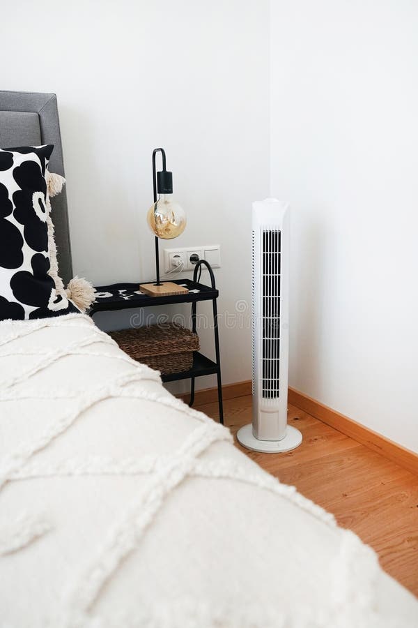 White Tower Fan Next To a Bed and Bedside Table with a Lamp in a Modern ...