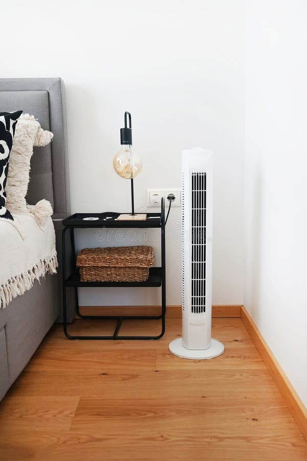 White Tower Fan Next To a Bed and Bedside Table with a Lamp in a Modern ...