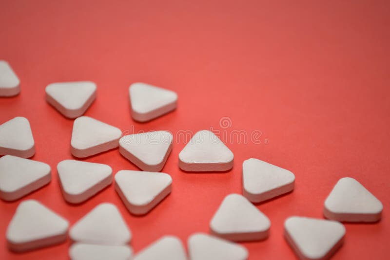 White Triangular Unusual Pills Dispersed on a Pink Background Closeup ...