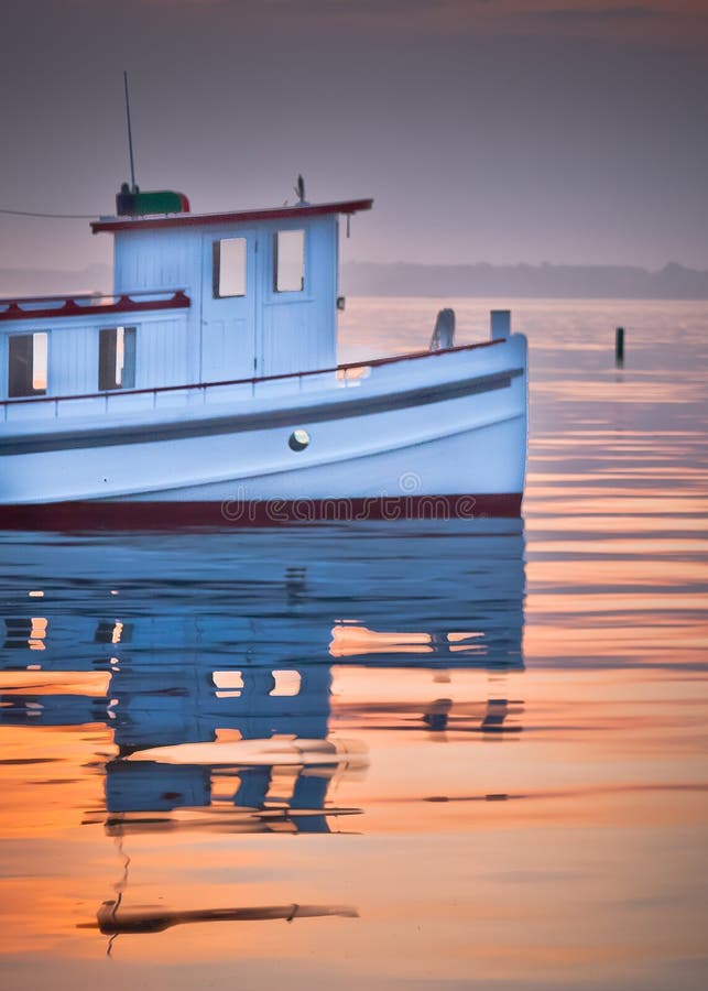 White Tugboat on a Beach at with the Ocean Reflecting Dusk Colors Stock ...