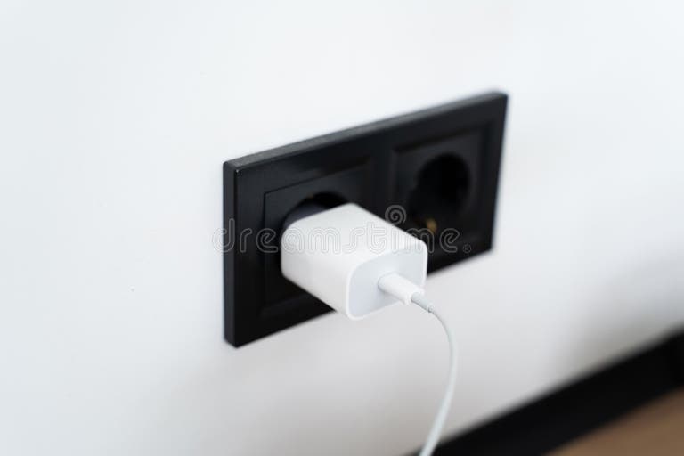 White USB Charger Plugged into Black Wall Socket in Modern Interior ...