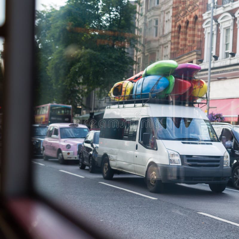 White Van in the Traffic with Many Colored Canoes on the Roof Stock ...