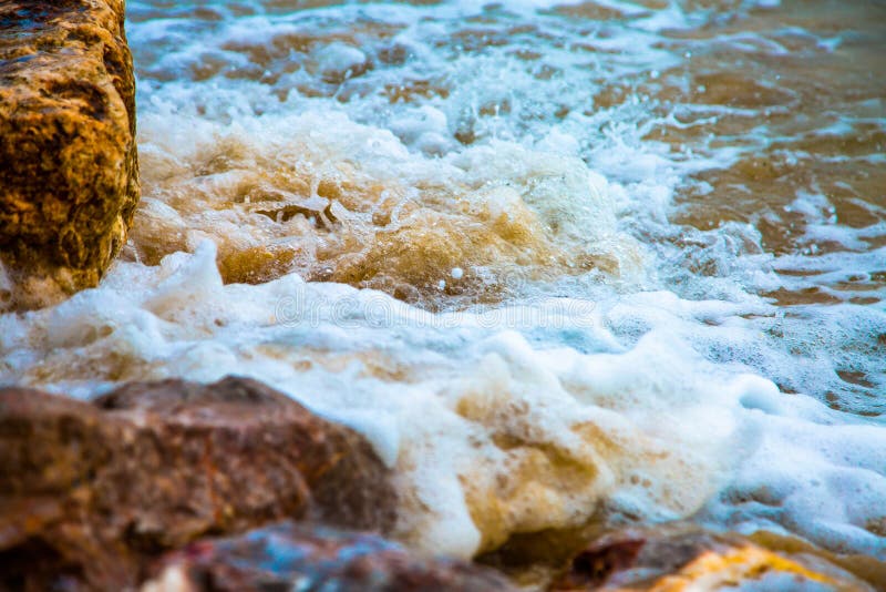 The White Wave Bumps the Brown Rocks at the Blue Sea on Brown Sand ...