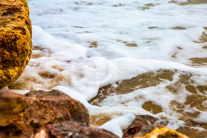The White Wave Bumps the Brown Rocks at the Blue Sea on Brown Sand ...