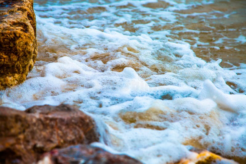 The White Wave Bumps the Brown Rocks at the Blue Sea on Brown Sand ...