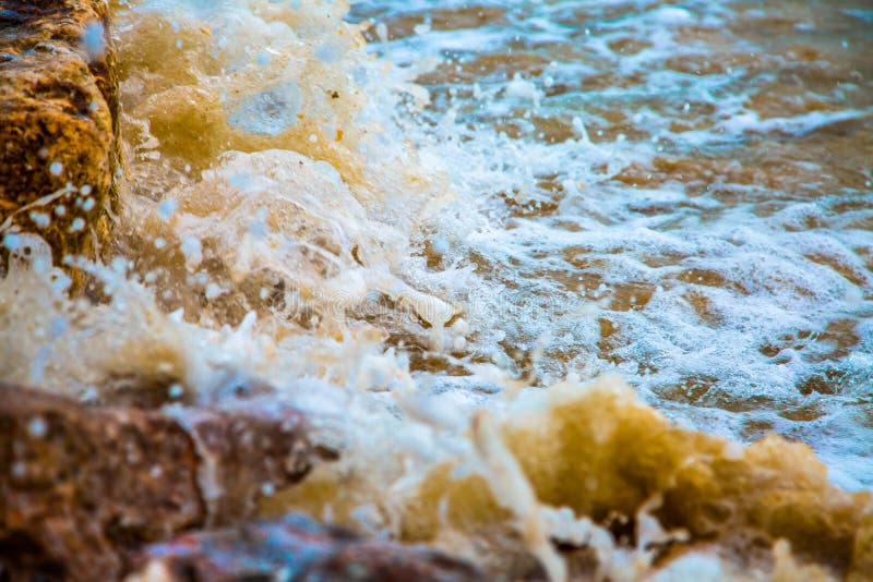 The White Wave Bumps the Brown Rocks at the Blue Sea on Brown Sand ...