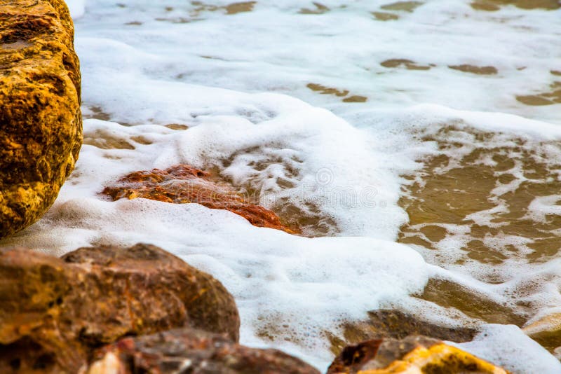 The White Wave Bumps the Brown Rocks at the Blue Sea on Brown Sand ...