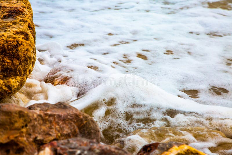 The White Wave Bumps the Brown Rocks at the Blue Sea on Brown Sand ...