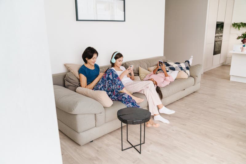 White Woman and Her Daughters Using Gadgets while Resting on Couch ...
