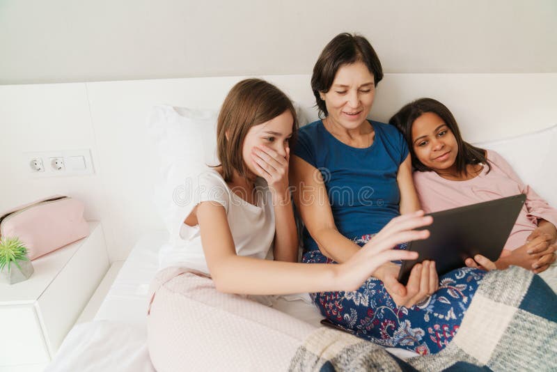 White Woman and Her Daughters Using Tablet Computer while Resting on ...
