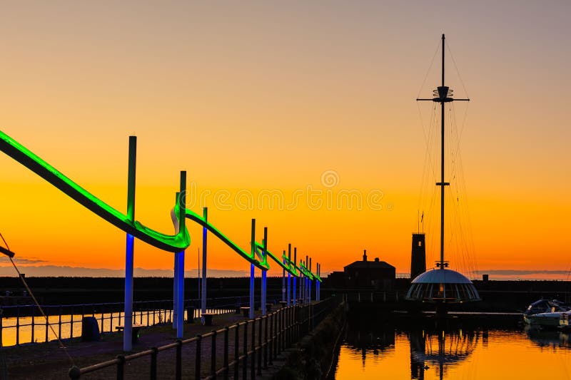 Millennium Wave Lit Up Against a Bright Orange Sunset Near the Harbor ...