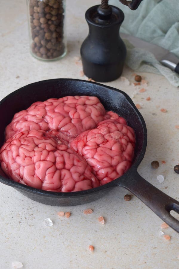 Whole Beef Brain in Black Pan on Kitchen Table beside Salt and Pepper Grinder. Rustic Culinary ...
