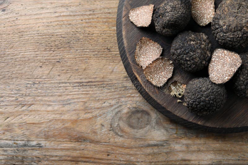Whole and Cut Black Truffles with Board on Wooden Table, Top View ...