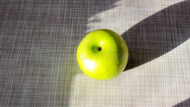A Whole Green Apple that is Illuminated by Sunlight with Sharp Shadows ...