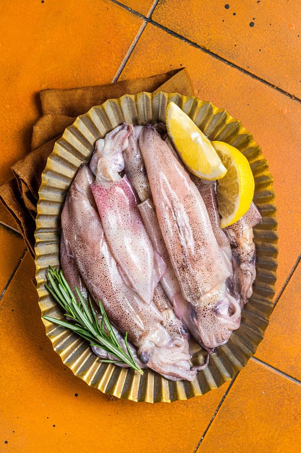 Whole Raw Squid with Herbs and Lemon, Fresh Seafood. Orange Background ...
