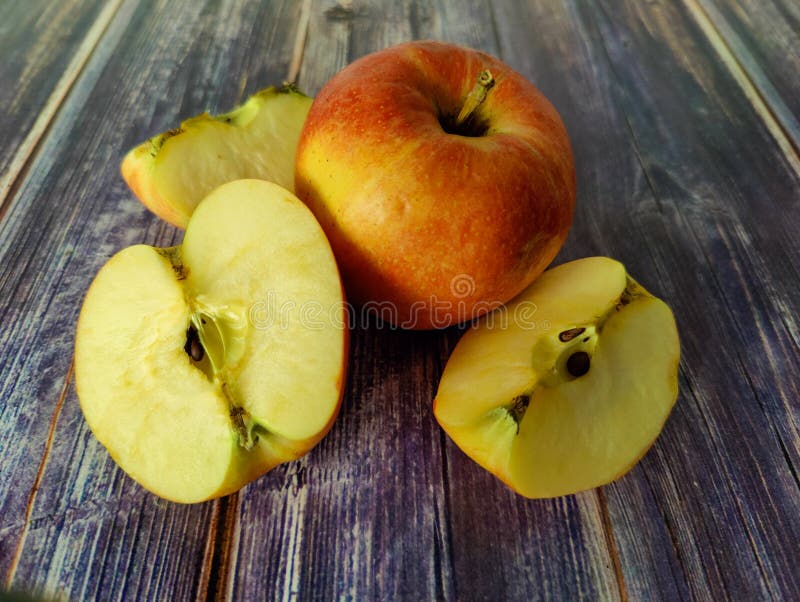 Whole Red Apple, Half and Two Quarter on a Wooden Table. Close-up Stock ...