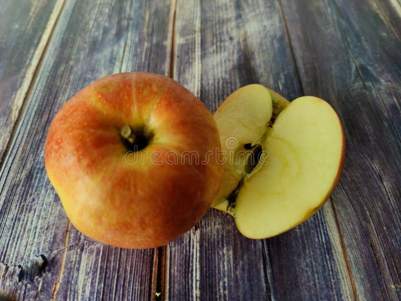 A Whole Red Apple and a Half on a Wooden Table. Close-up Stock Photo ...