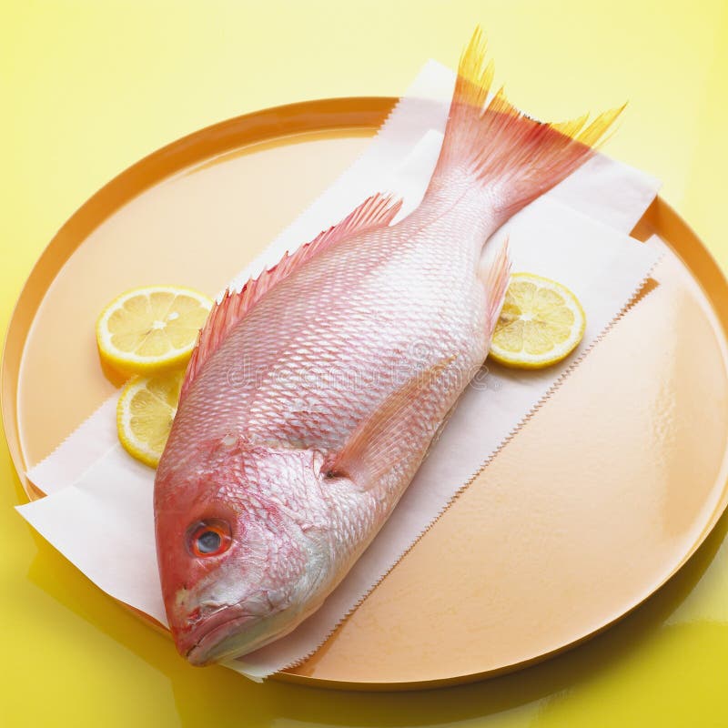 Whole Red Snapper Fish on a Yellow Plate with Lemons on the Side Stock ...