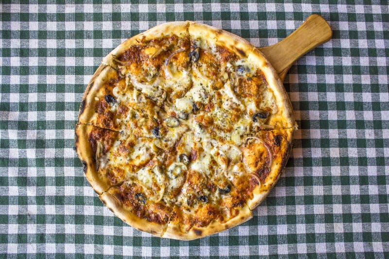 A Whole Round Pizza on a Wooden Plate with a Handle on a Table with a ...