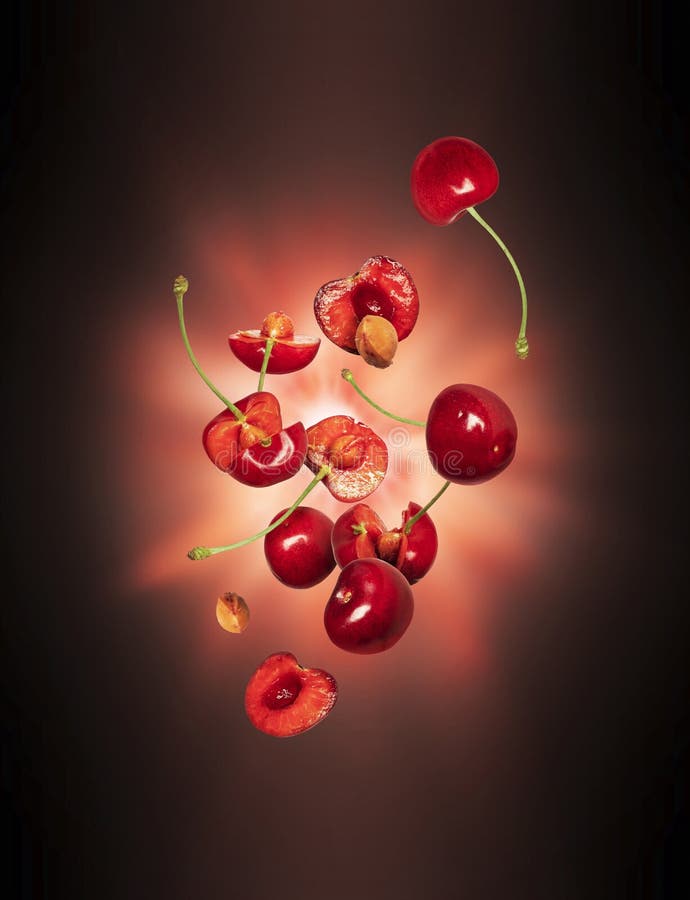 Whole and Sliced Fresh Cherries in the Air with Flash of Light in the ...