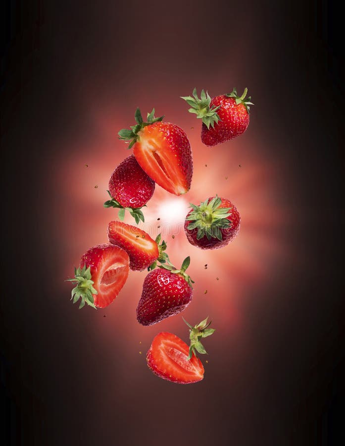 Whole and Sliced Fresh Strawberries in the Air with Flash of Light in ...