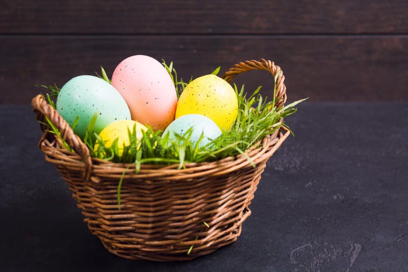 Wicker Basket with Natural Grass and Painted Eggs with Pastel Colors on ...