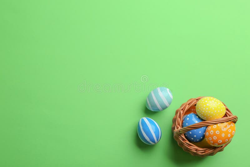 Wicker Basket with Painted Easter Eggs on Color Background, Top View ...