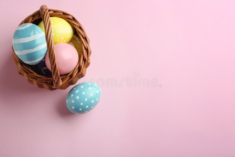 Wicker Basket with Painted Easter Eggs on Color Background, Top View ...