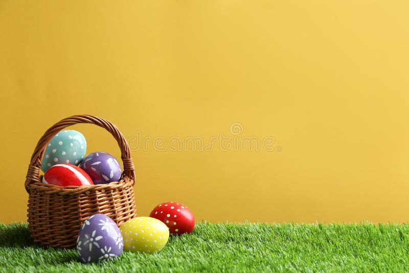 Wicker Basket with Painted Easter Eggs on Green Grass Against Color ...