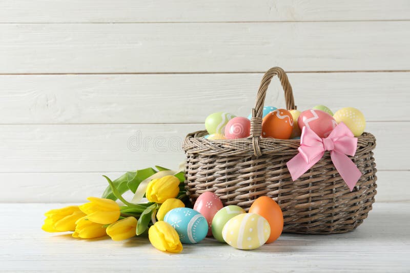 Wicker Basket with Painted Easter Eggs and Spring Flowers on Table ...