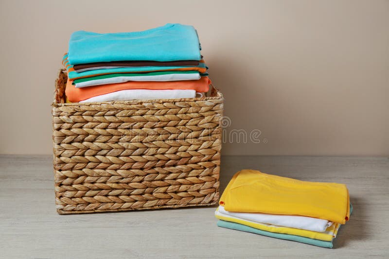 Wicker Laundry Basket with Clean Clothes on Floor Near Beige Wall Stock ...