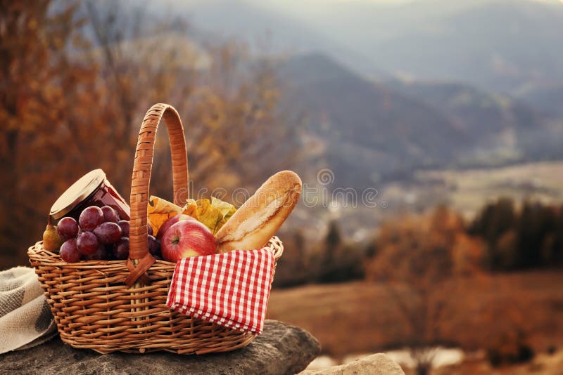 Wicker Picnic Basket with Different Products on Rock in Mountains ...