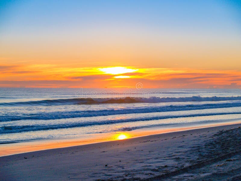 Wide Beach Image As Sun Rises Above Clouds on Horizon Stock Photo ...