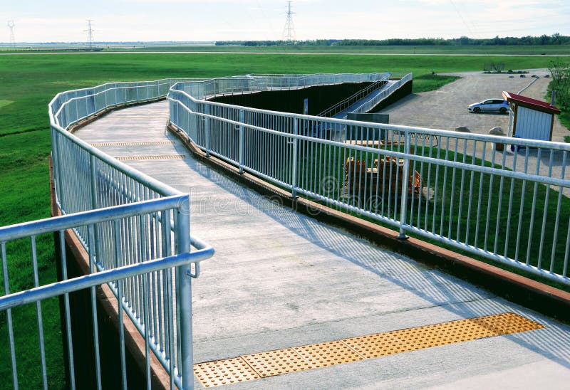 Wide Concrete Walkway with Railings on Both Sides, Sloping Down. Field ...