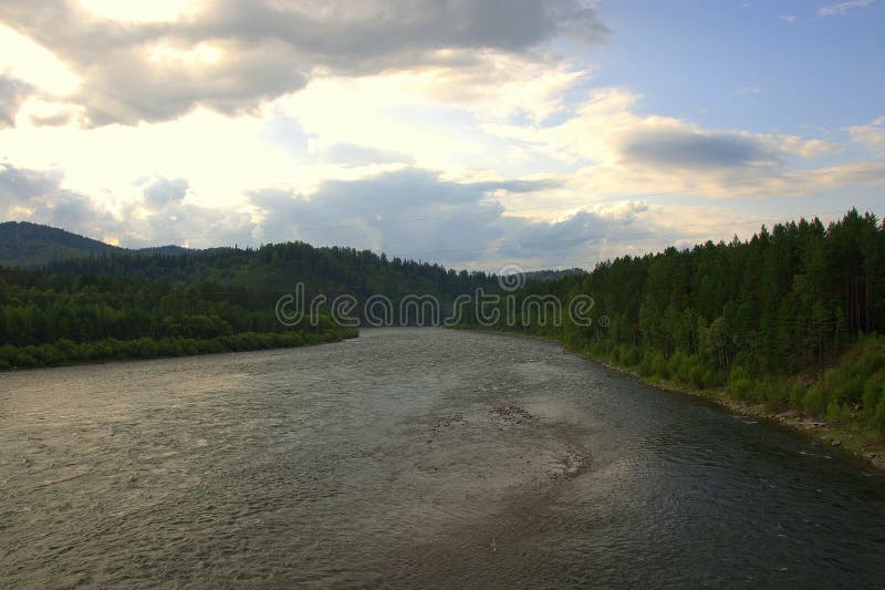 A Wide, Full-flowing River Flowing through the Forest Under Dramatic ...