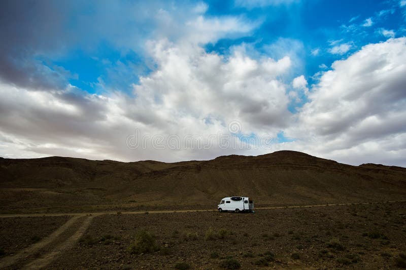 Wide Open Desert Landscape with a Parked Camper Amidst Dramatic Clouds ...