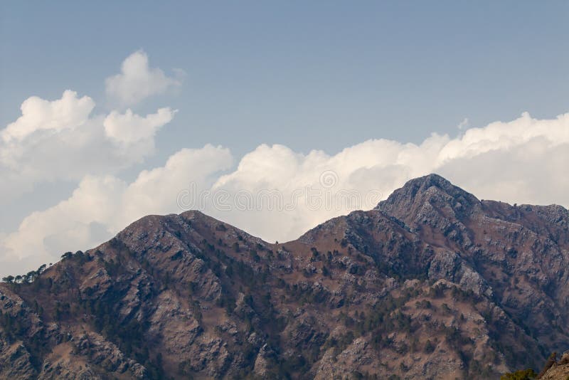 Wide Shot of a Cloud Covered Sky with a Huge Mountain and Two Peaks in ...