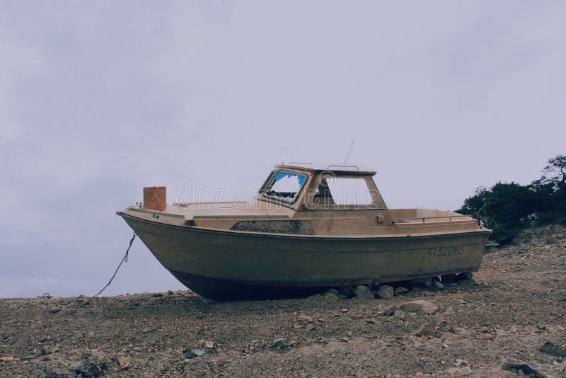 Wide Shot of a Vintage Brown Boat on a Rocky and Sandy Surface ...