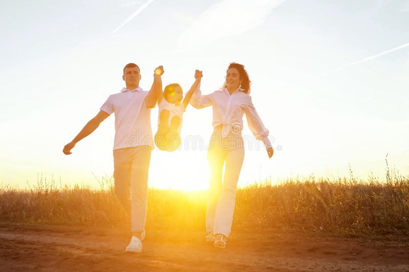 Wife and Husband Lift Daughter Walking Against Setting Sun Stock Photo ...